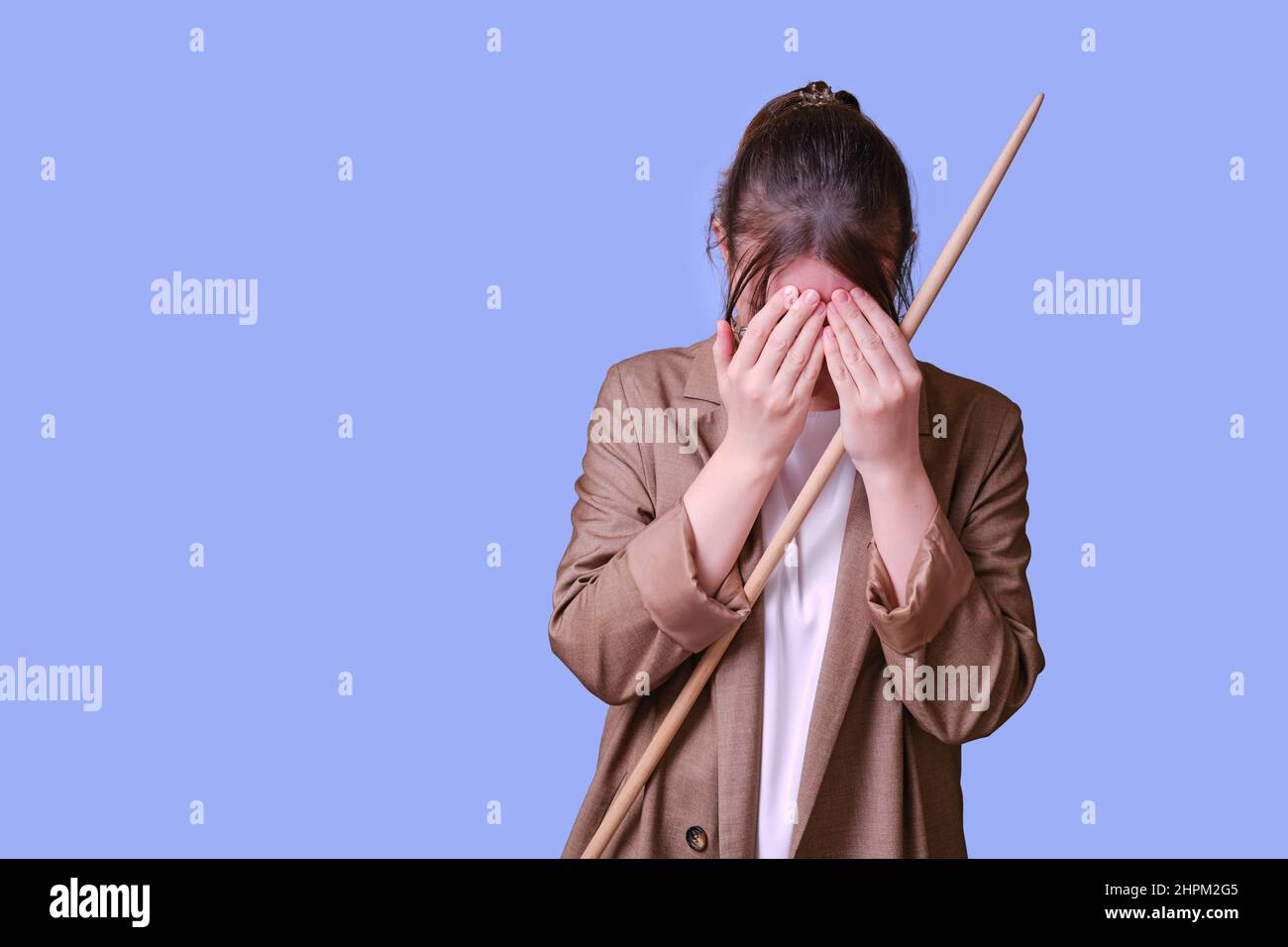 Crying woman teacher with pointer on studio blue background, copy space ...
