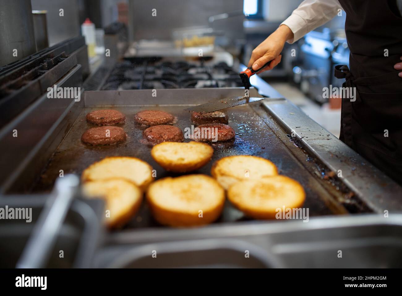 Close-up of professional female chef preparing burgers indoors in ...