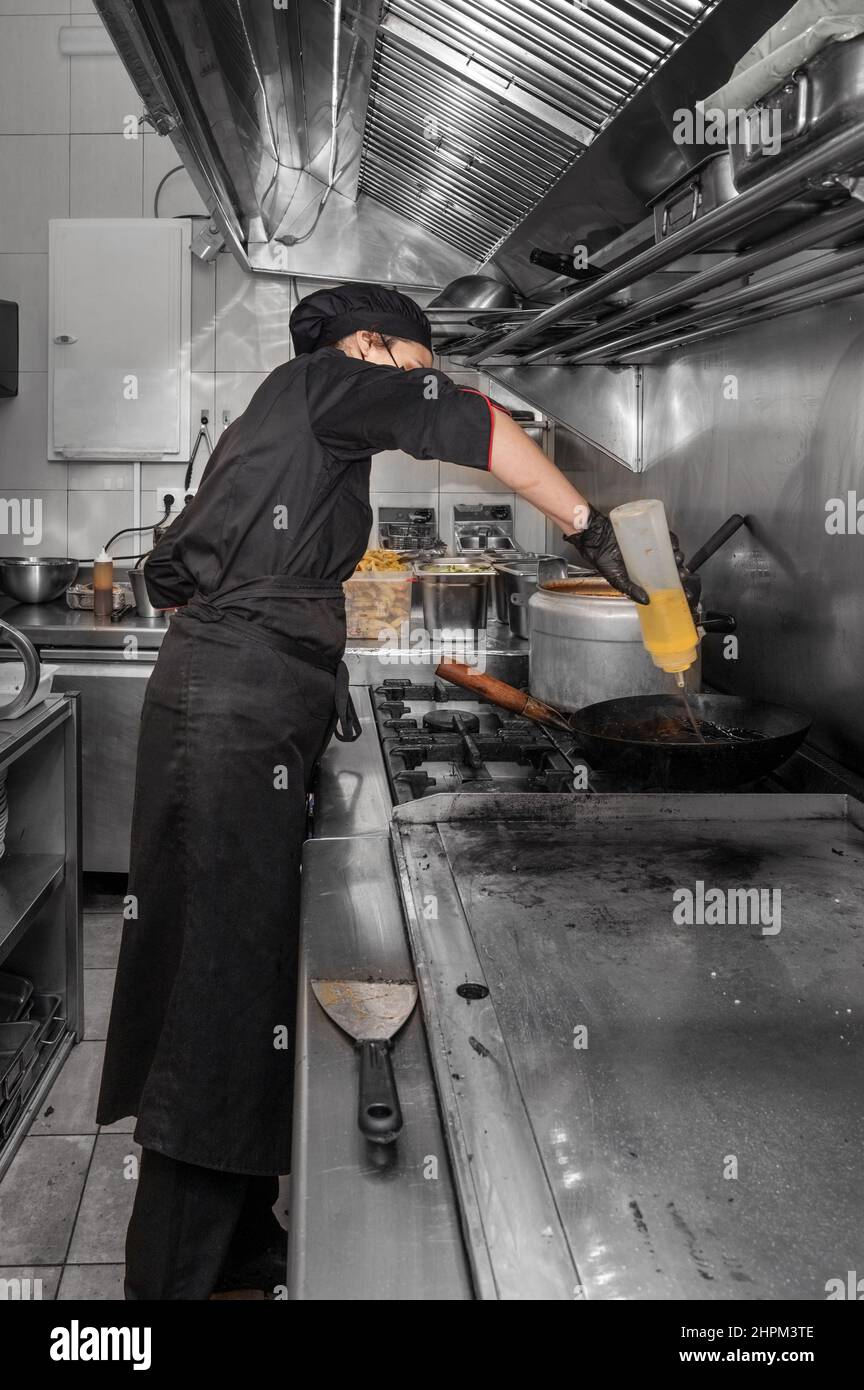 Side view of female chef working in commercial kitchen. High quality ...