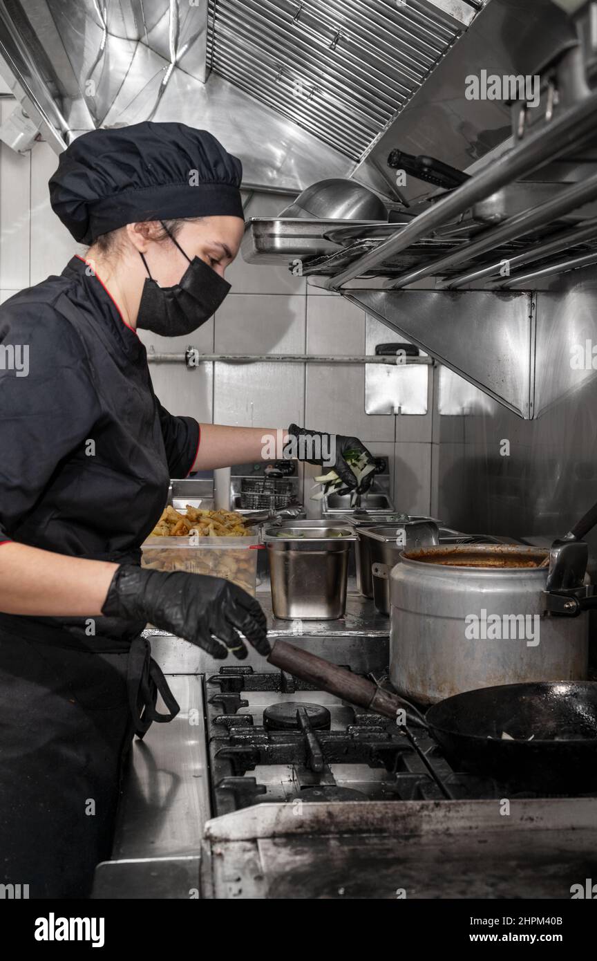 Side view of female chef working in commercial kitchen. High quality ...