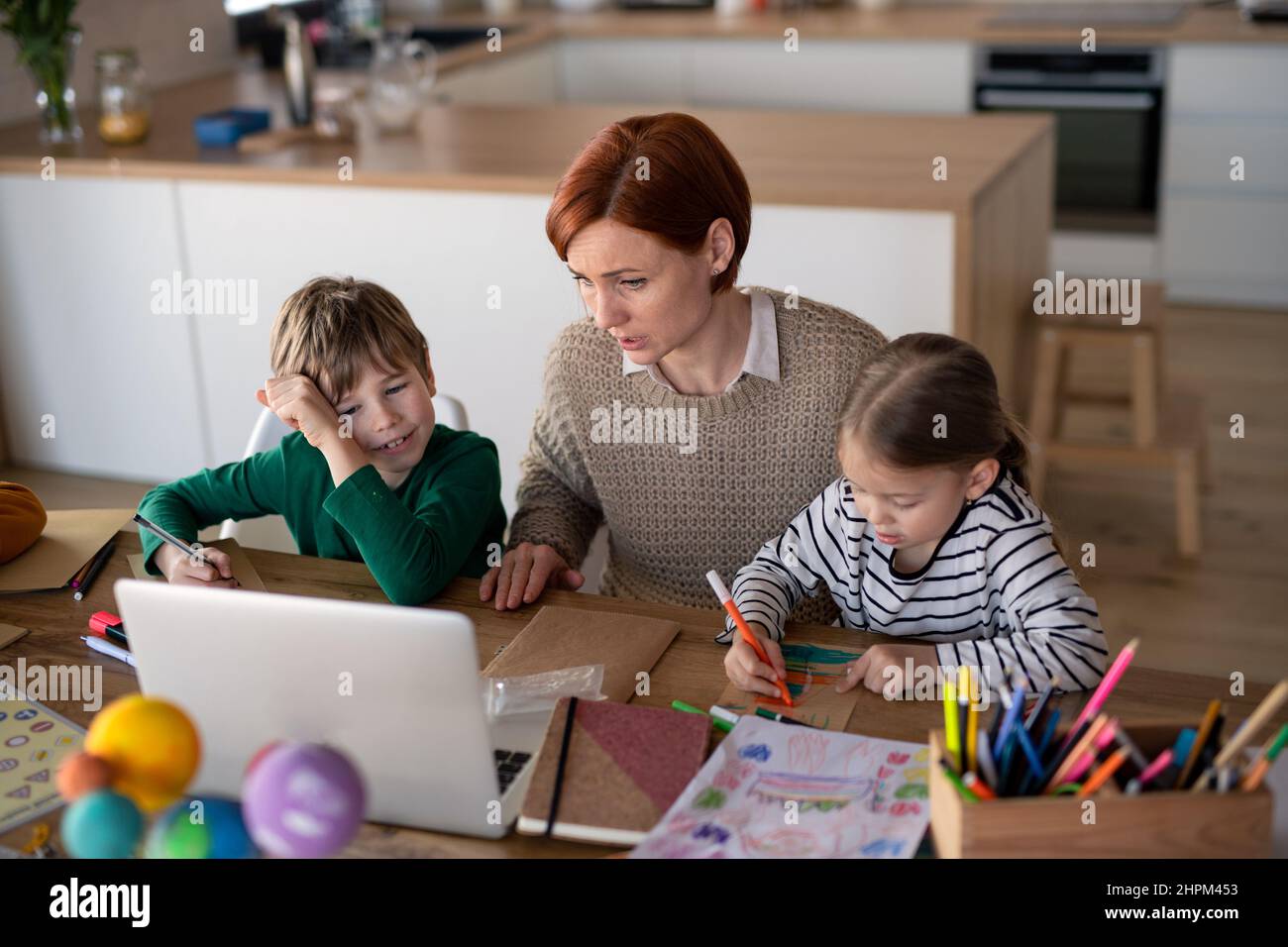 Mother of little children supervising them when distance learning and ...