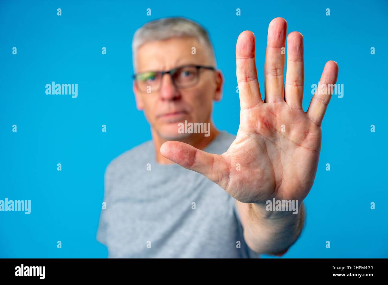 Middle age senior man over blue background doing stop sign with palm of ...