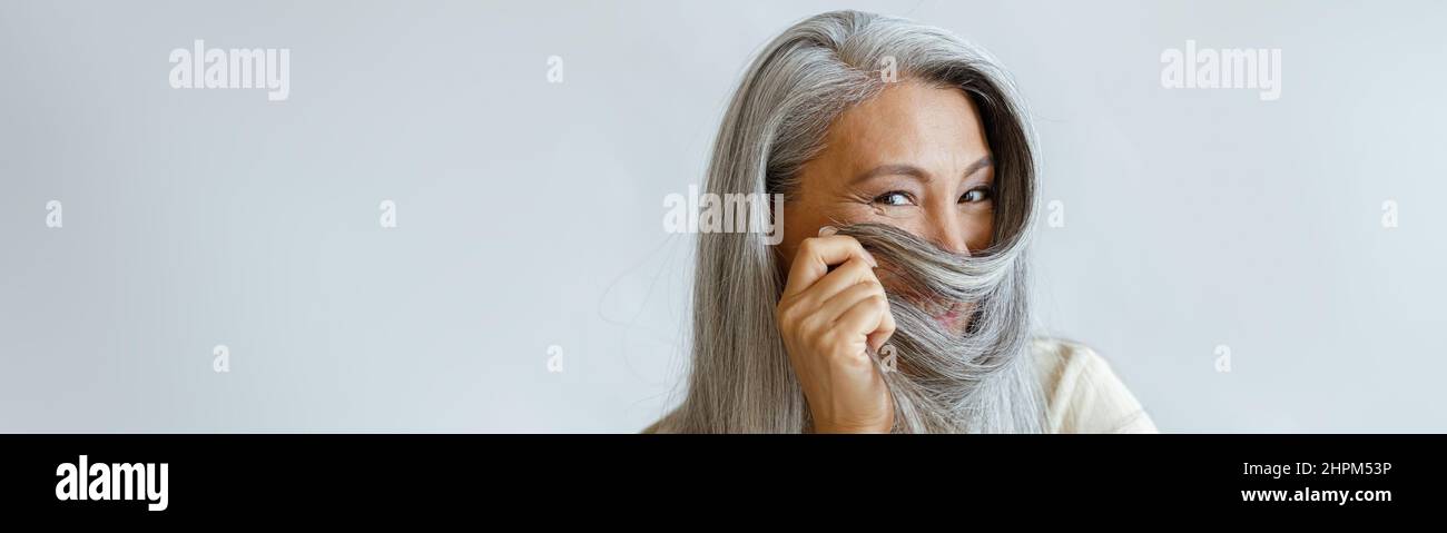 Positive middle aged Asian lady uses hoary hair as niqab sitting on ...