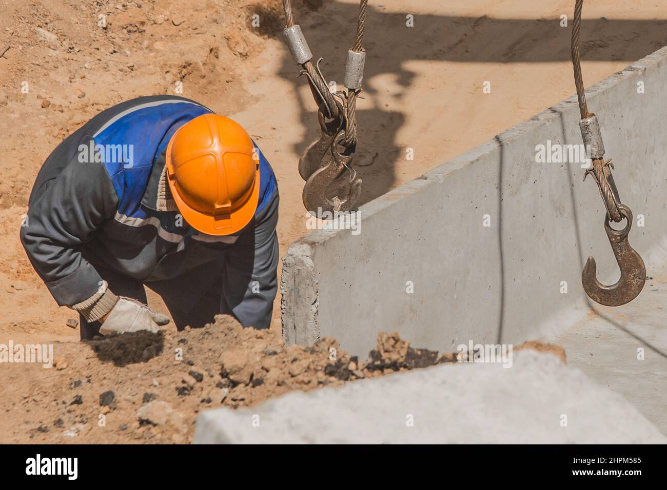 An industrial worker in overalls and a protective helmet attaches a ...