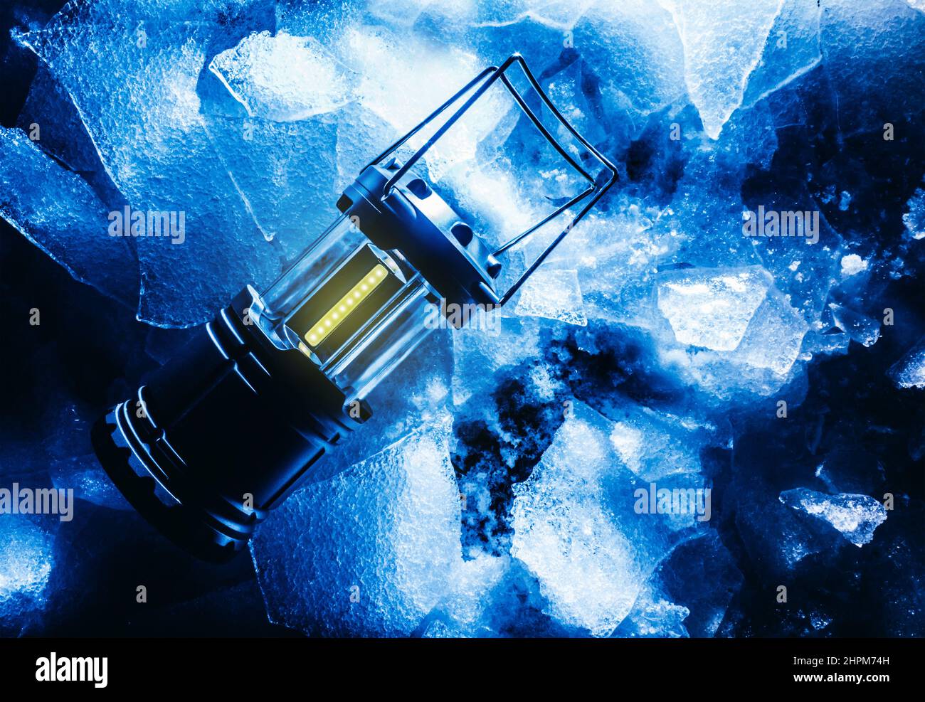 Photo of camping led shining lantern laying on cracked ice surface ...