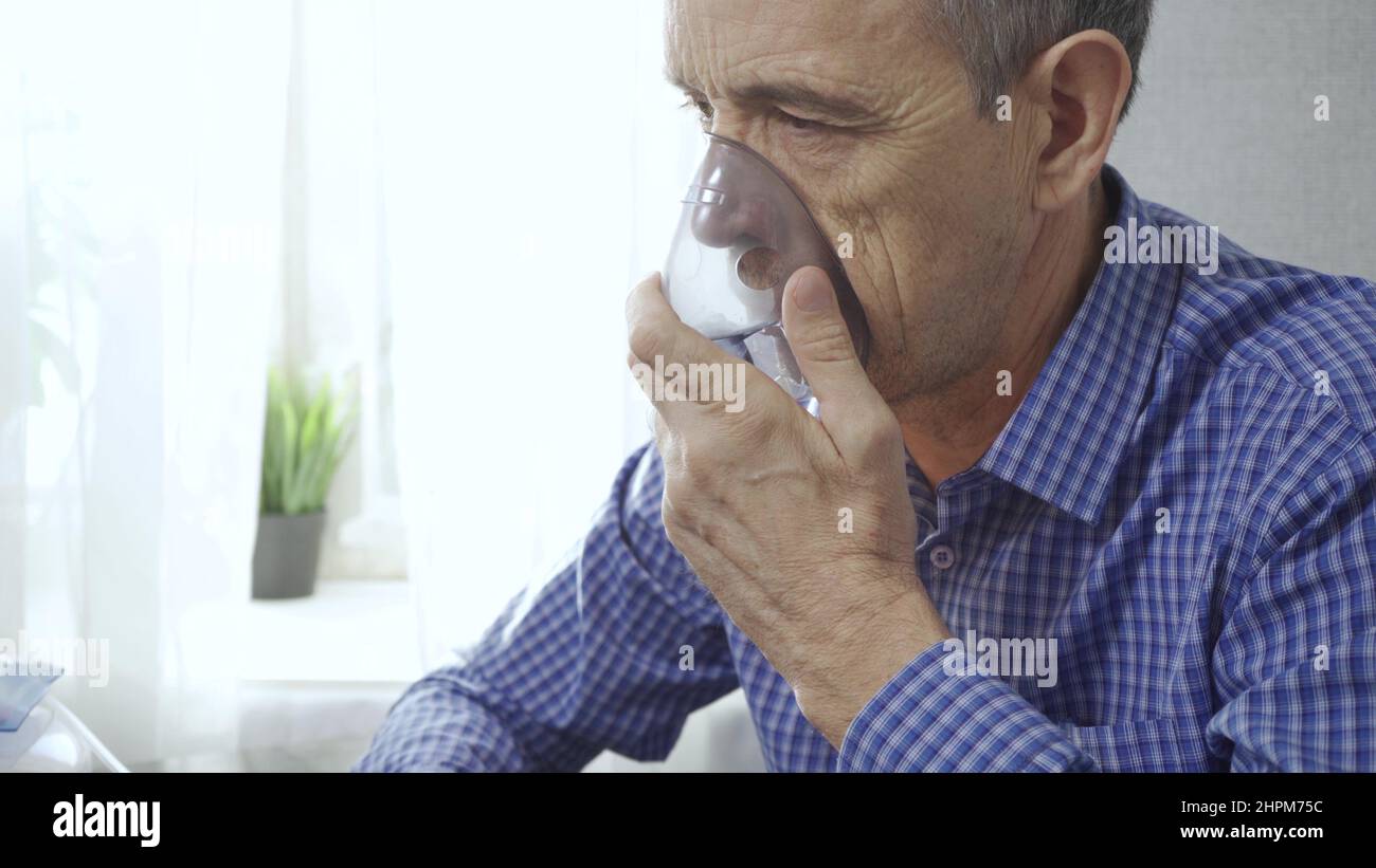 An elderly man is using an inhaler. Treatment of airway inflammation ...