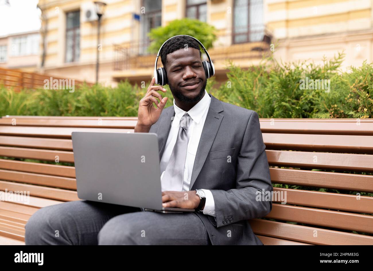 African american businessman in wireless headphones using laptop and ...