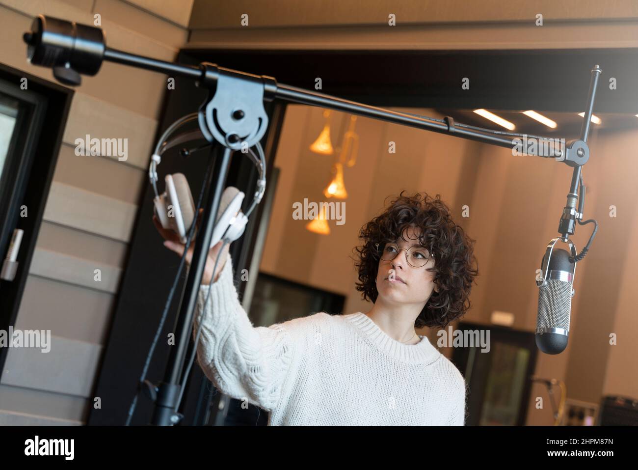 A young curly hair singer woman with glasses recording a song in a real ...
