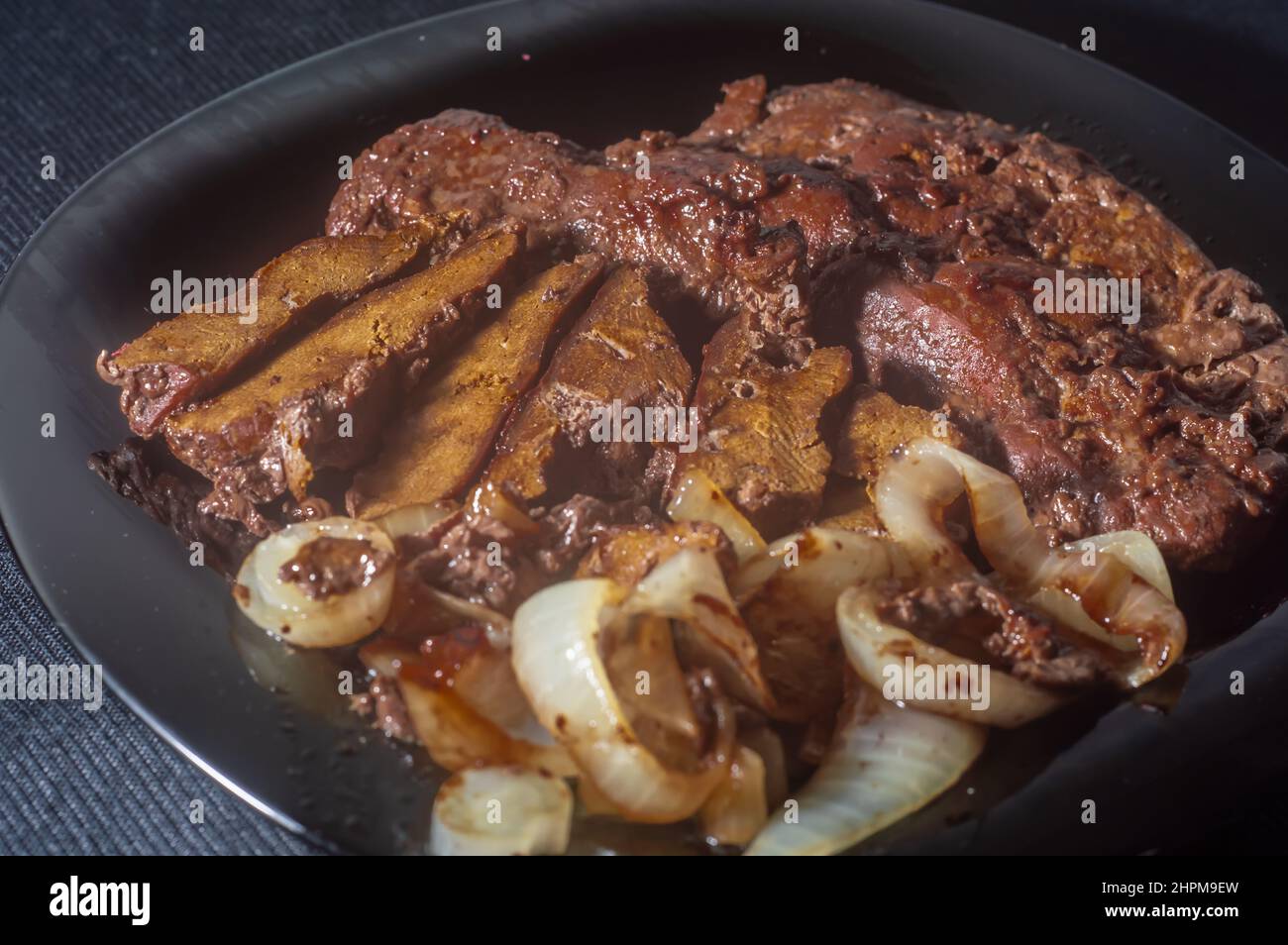Fried ox liver, Brazilian food and placed on a black plate with onions ...