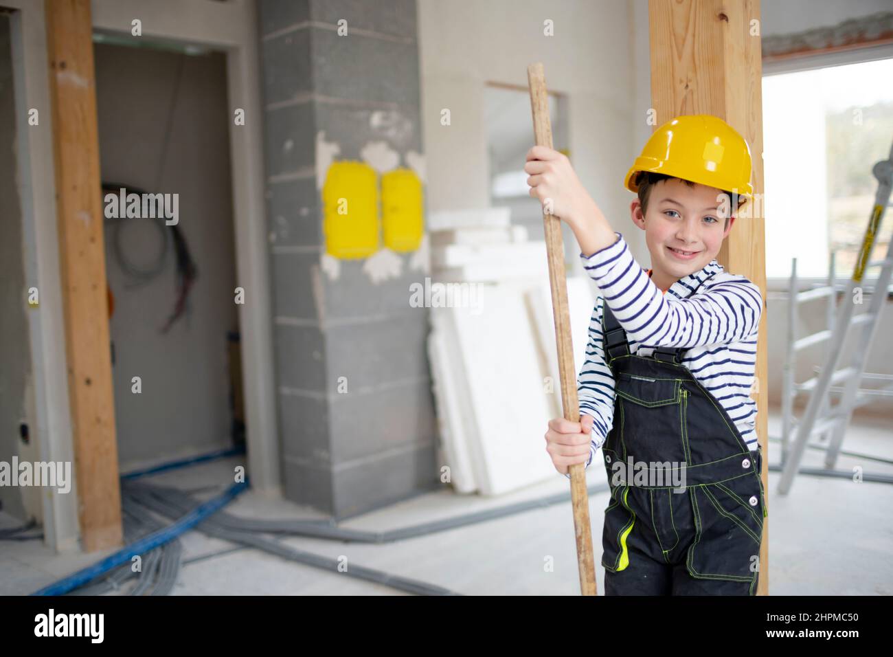 cool boy with yellow helmet posing on construction site in a house with ...