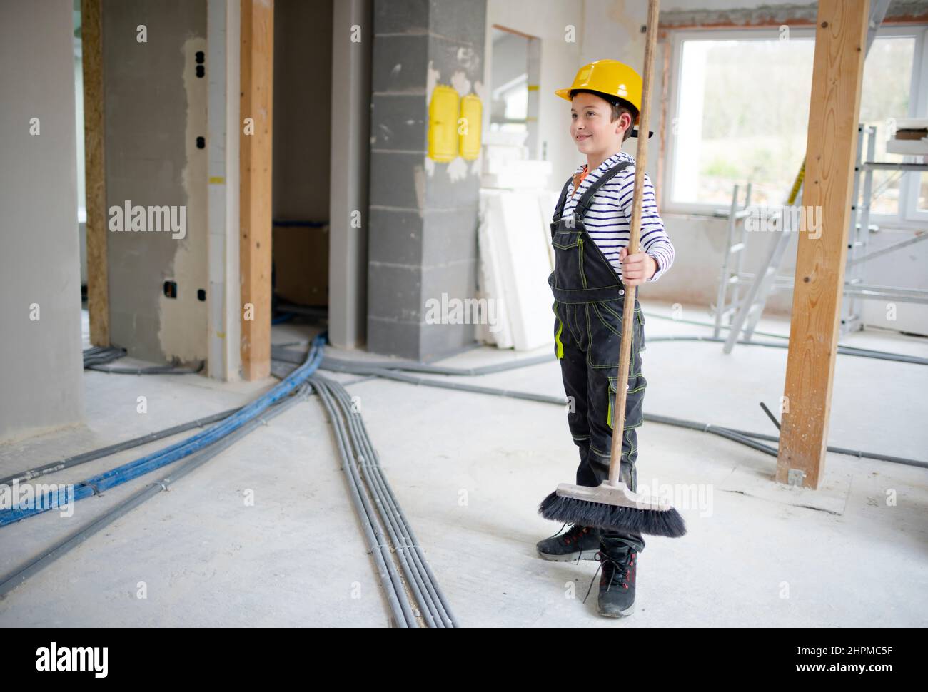 cool boy with yellow helmet posing on construction site in a house with ...