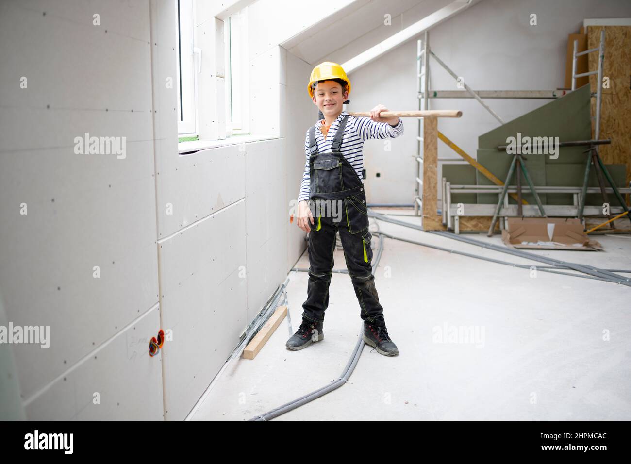 cool boy with yellow helmet posing on construction site in a house with ...