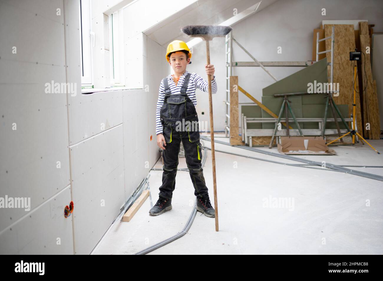 cool boy with yellow helmet posing on construction site in a house with ...