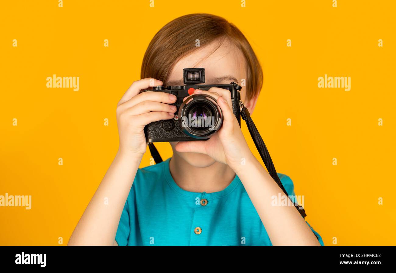 Little boy on a taking a photo using a vintage camera. Child in studio ...