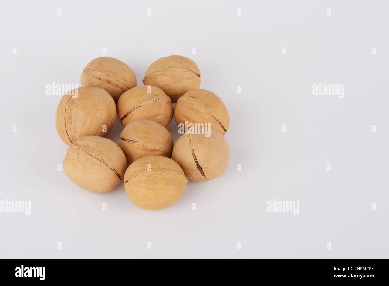Walnuts on a white background are laid out in the shape of a flower ...