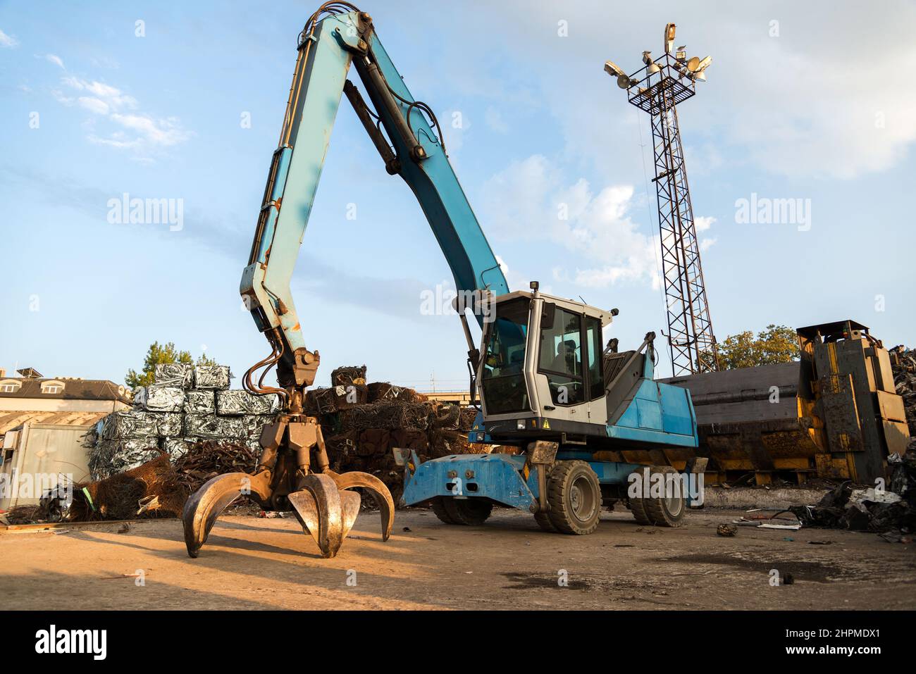 Large tracked excavator working a steel pile at a metal recycle yard ...