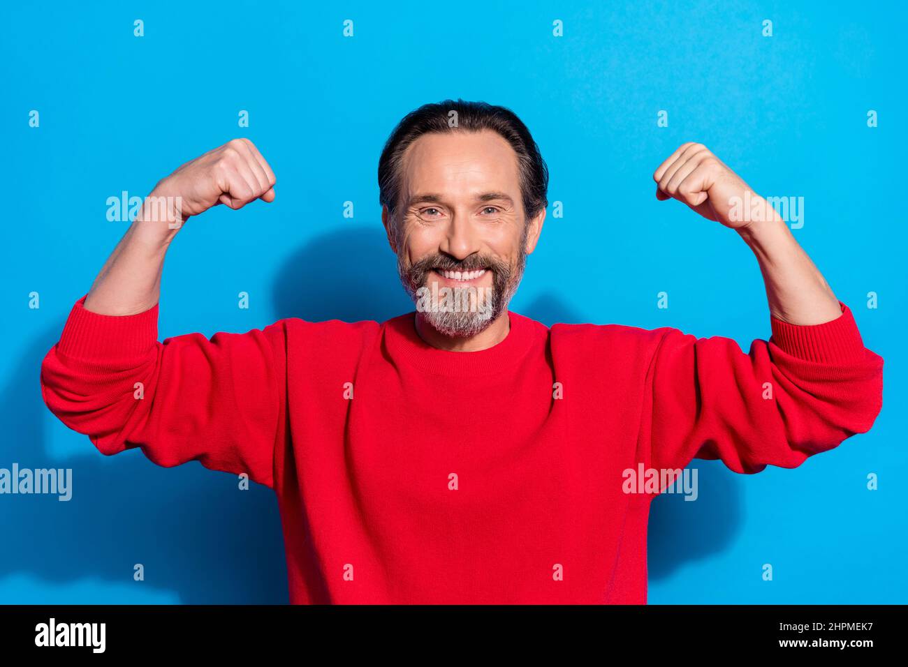 Portrait of attractive cheerful strong man demonstrating muscles ...