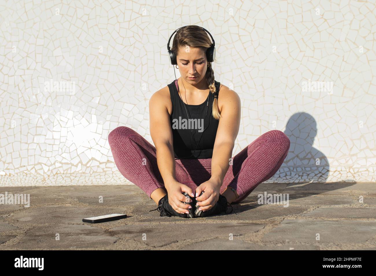 Young woman stretching while listening to music Stock Photo - Alamy