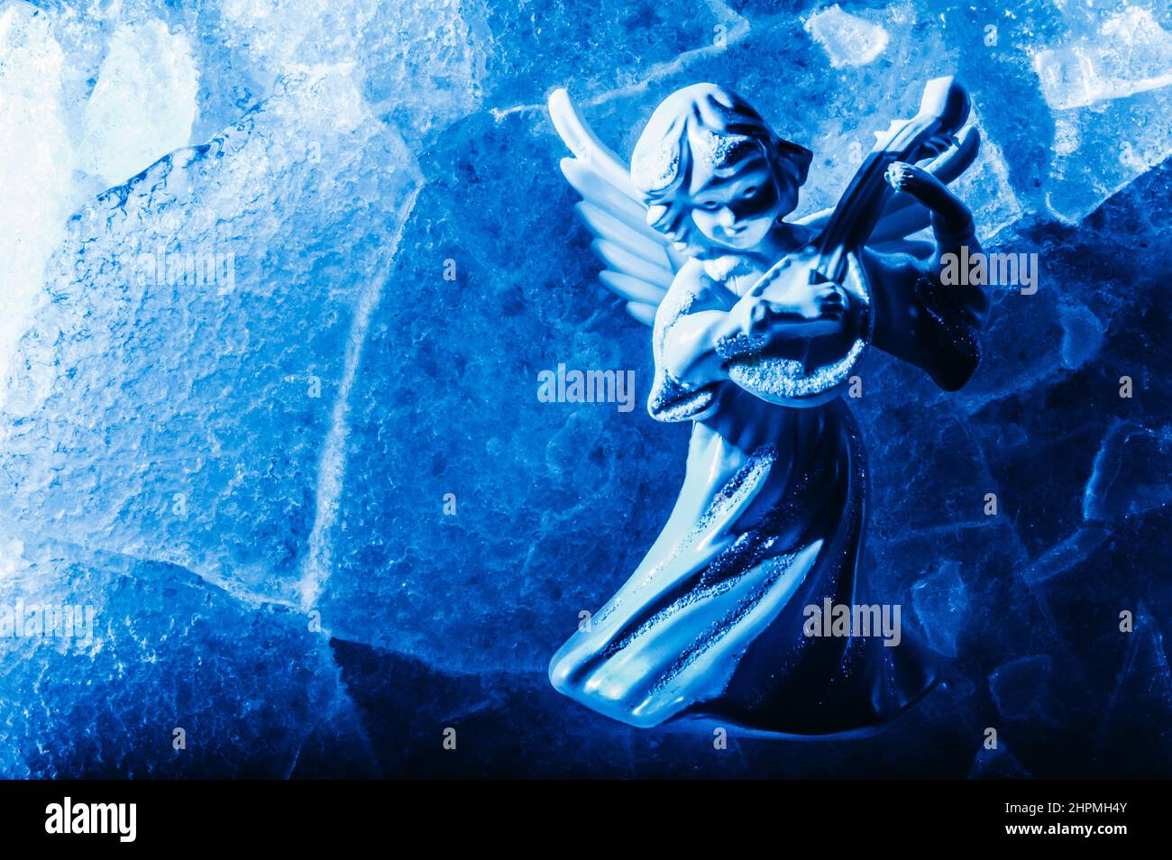 Close up photo of blue toned ice angel miniature playing the lute and ...