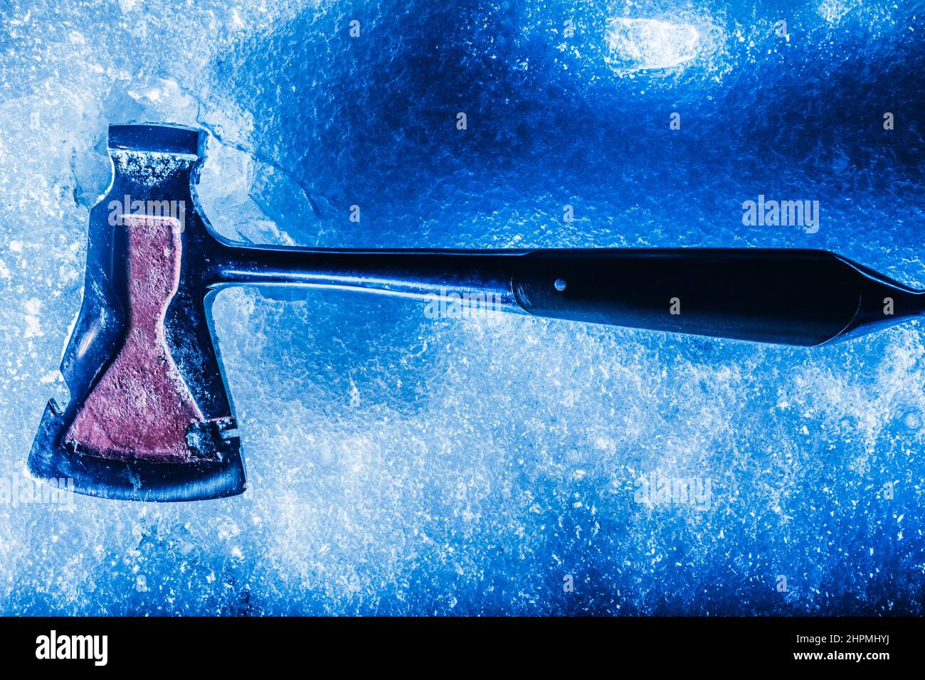 Photo of blue toned old fashioned ice hatchet laying on frozen snow ...