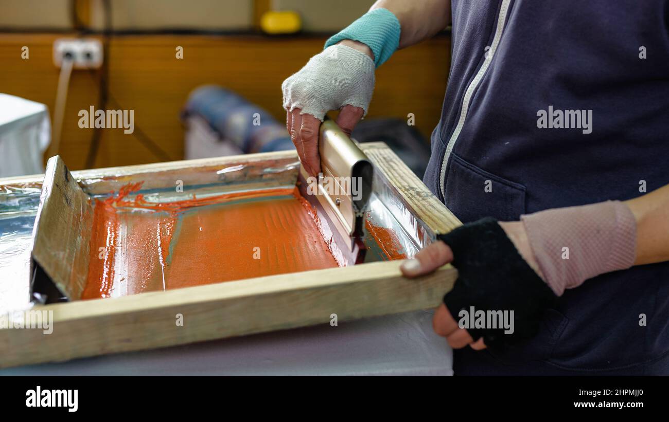 serigraphy production selective focus photo. male hand with a squeegee ...