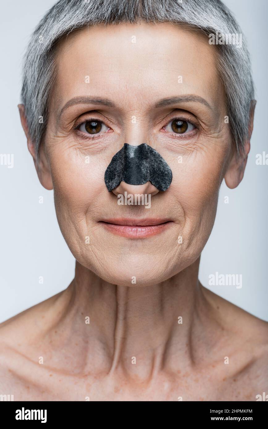 close up of smiling middle aged woman with grey hair and patch on nose ...