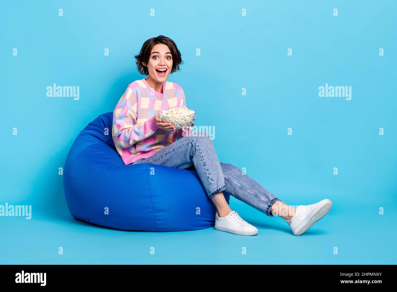 Full size profile side photo of young girl sit beanbag eat pop corn ...
