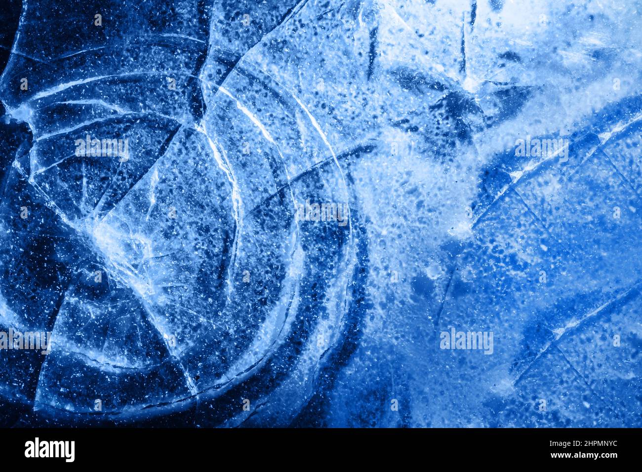 Photo of blue toned frozen circle cracked and scratched ice surface ...