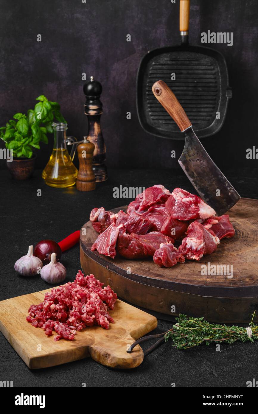 Chopping fresh beef meat for goulash or stew on wooden chopping stump ...