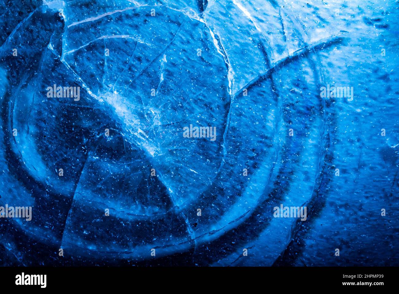 Close up photo of blue toned frozen circle cracked and damaged ice ...