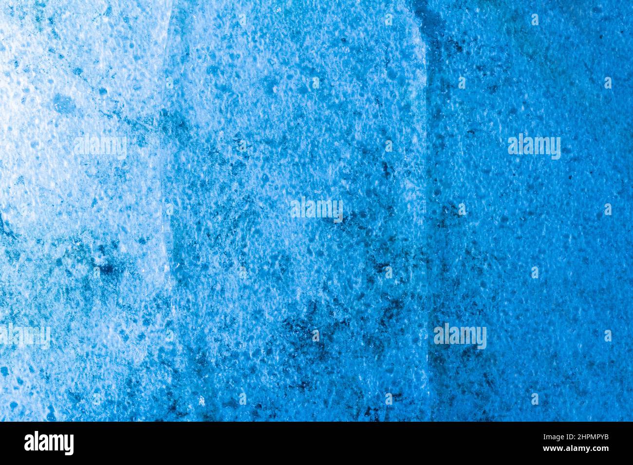 Photo of blue toned frozen transparent ice surface with snow texture ...