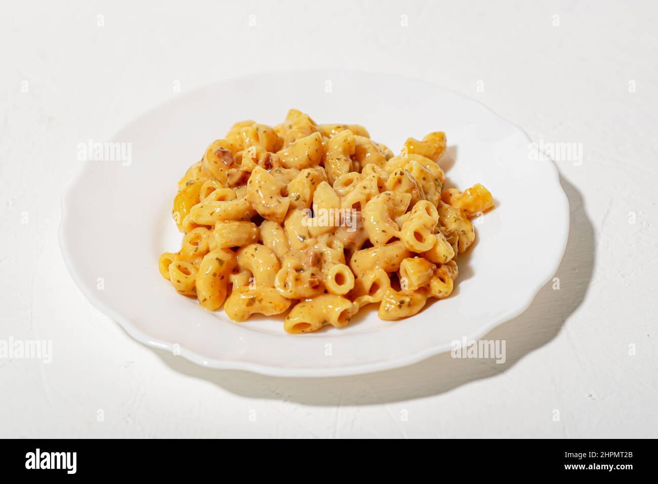 curly pasta with sauce on a white plate. Minimalism. White background ...