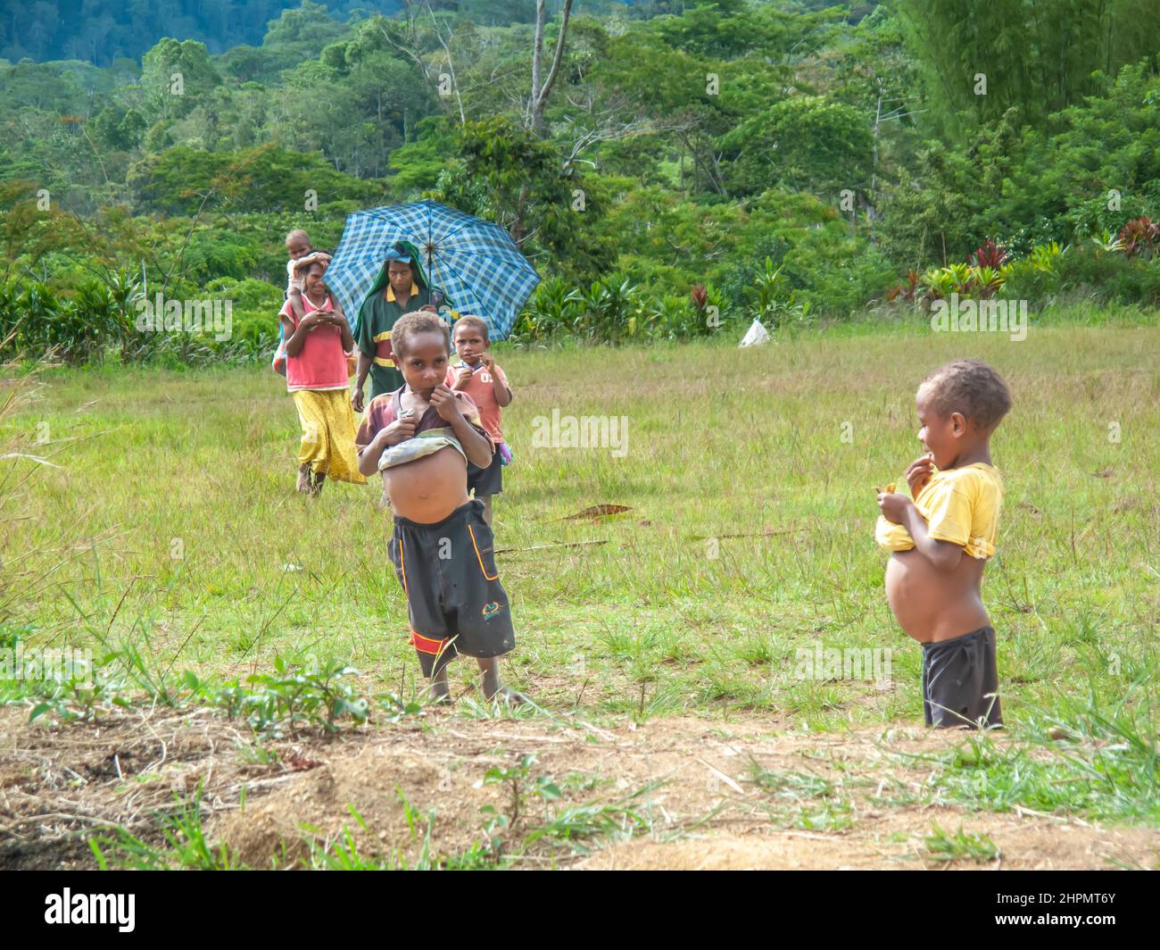 Women and children in highland PNG. Two boys have shirts pulled up ...