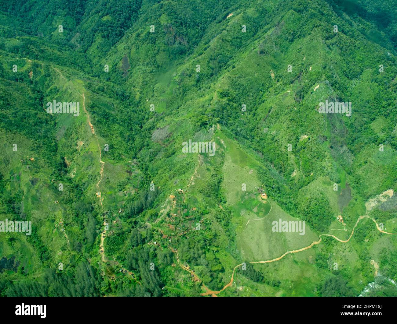 Aerial view of green mountains in Papua New Guinea. Steep slopes show ...
