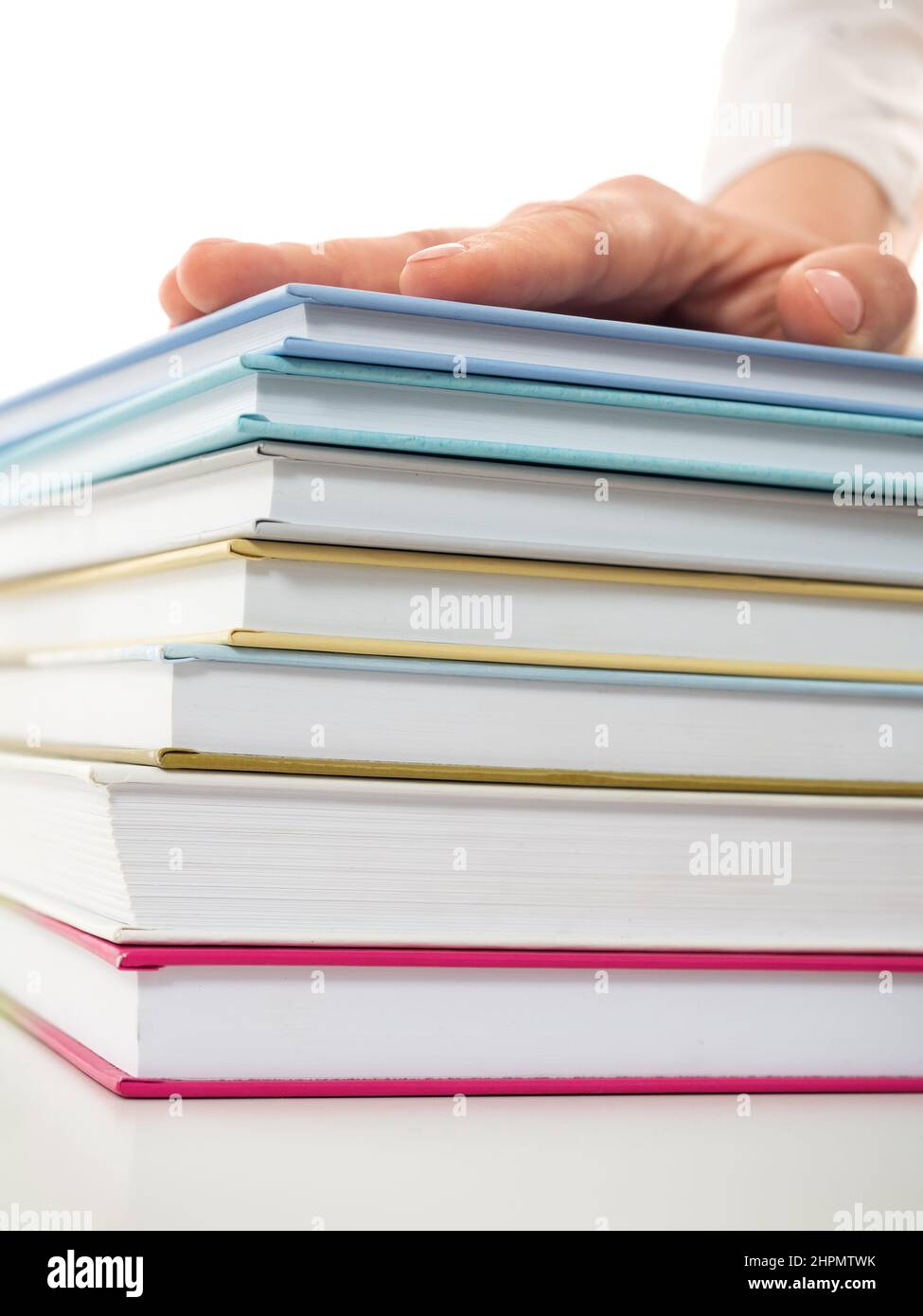 Stack of books with hand on top of it Stock Photo - Alamy