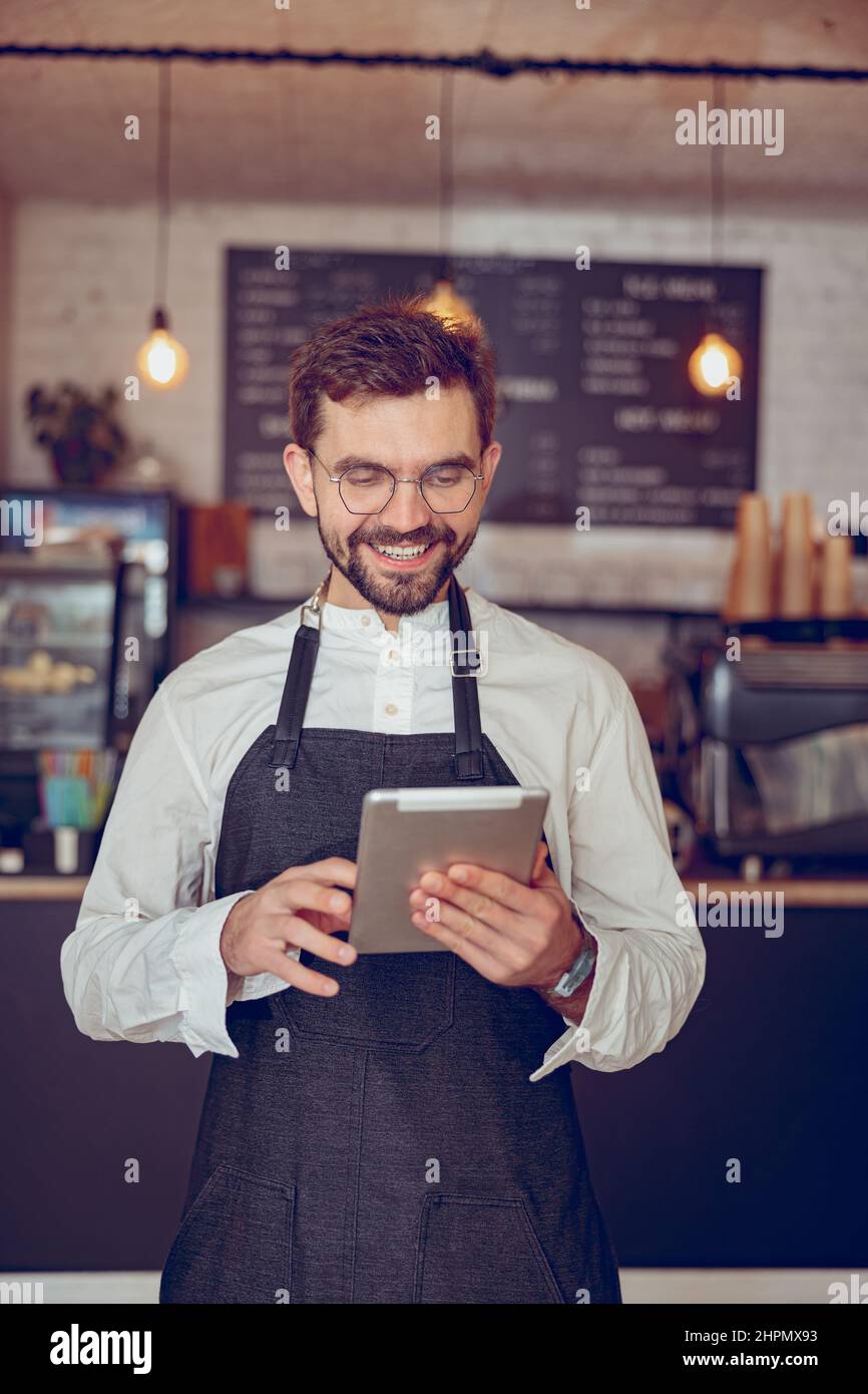 Cheerful man barista using tablet computer in cafe Stock Photo - Alamy