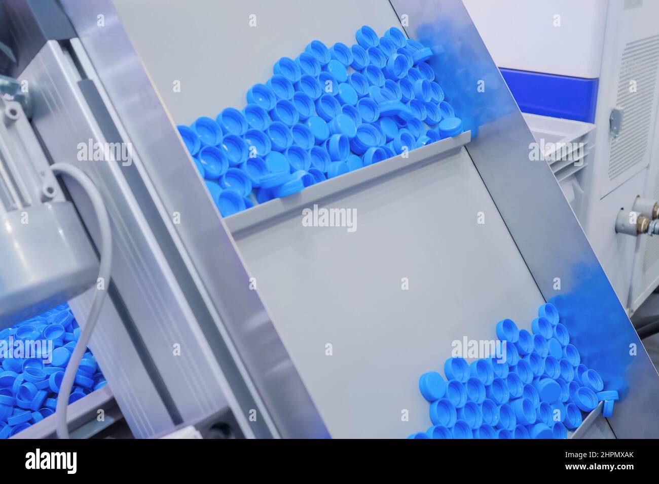 Many blue plastic bottle caps moving on conveyor belt - production line ...