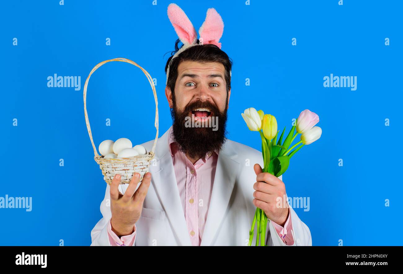 Easter day. Rabbit Man in bunny ears with tulips and basket eggs ...