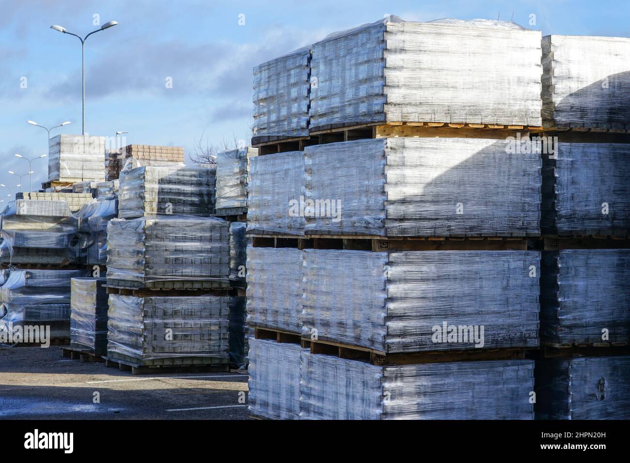 A pile of new paving slabs on a wooden pallets wrapped in transparent ...