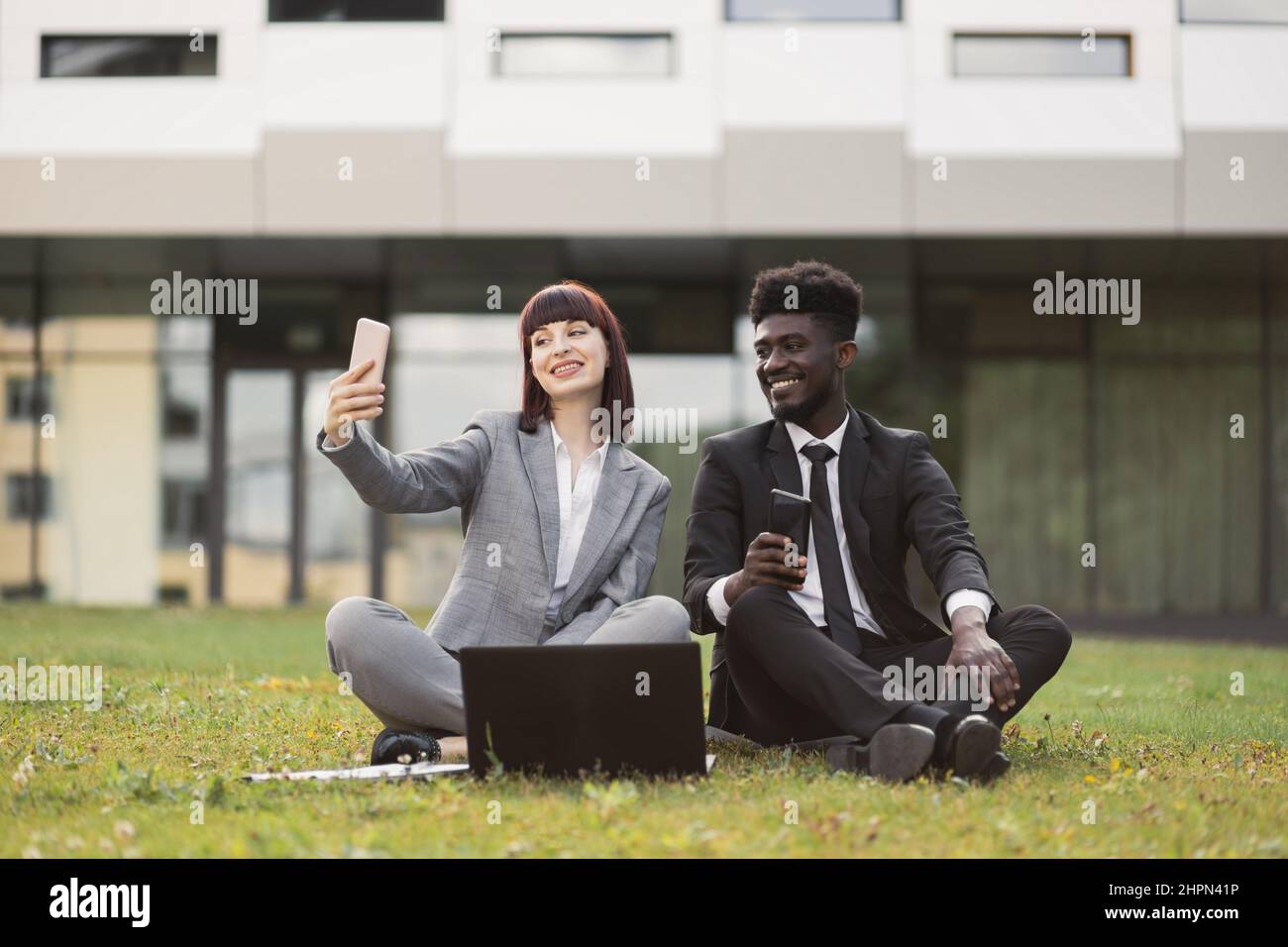 Young business colleagues having fun outdoors, sitting outside office ...