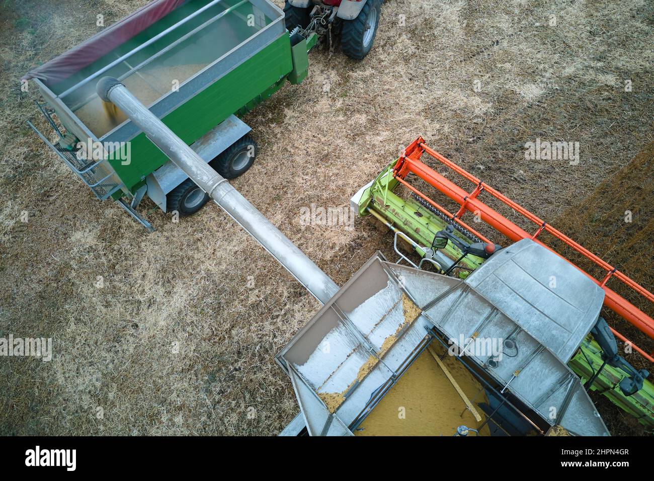 Aerial view of combine harvester unloading grain in cargo trailer ...