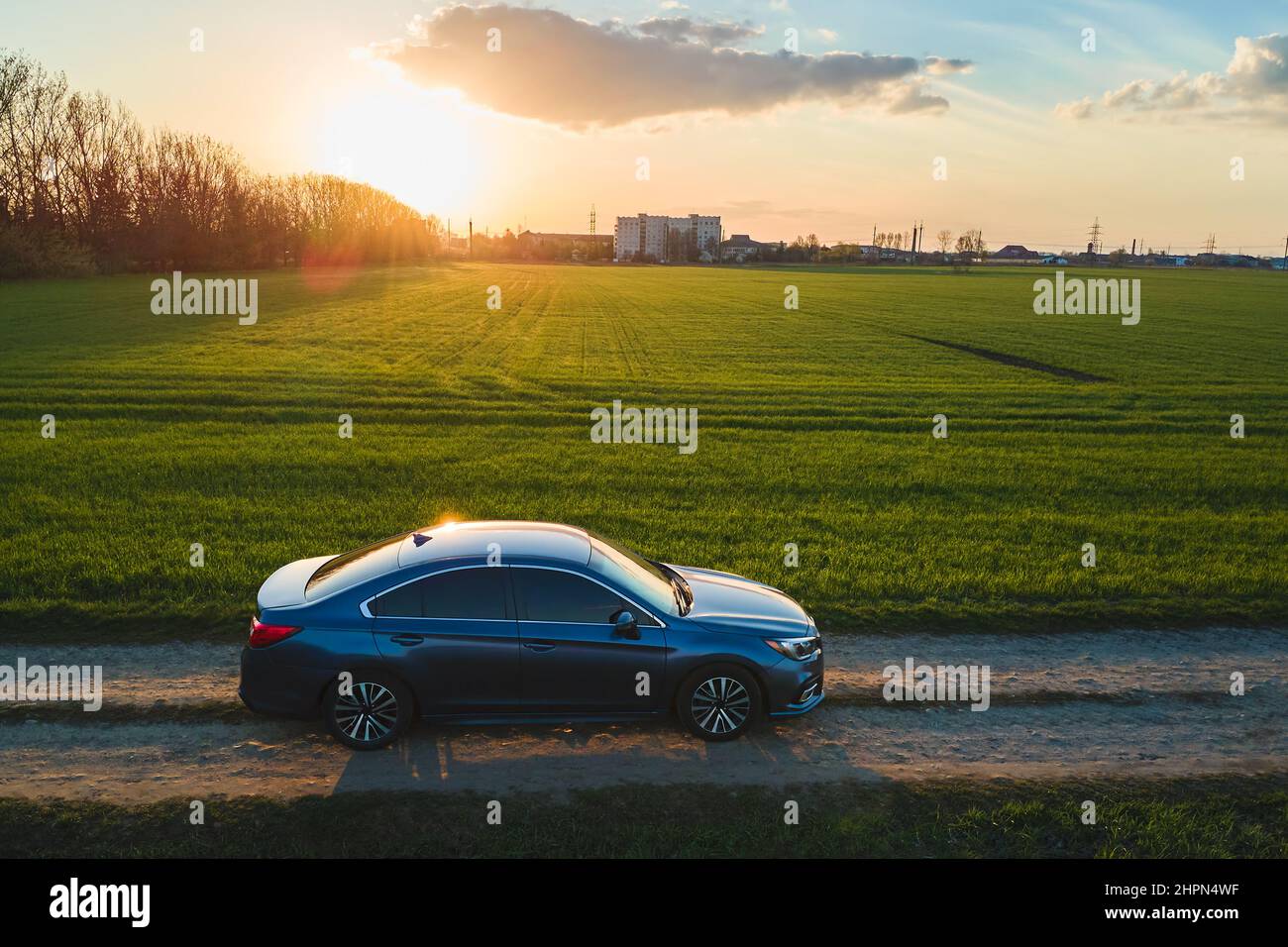 Aerial view of sedan car driving fast on dirt road at sunset. Traveling ...