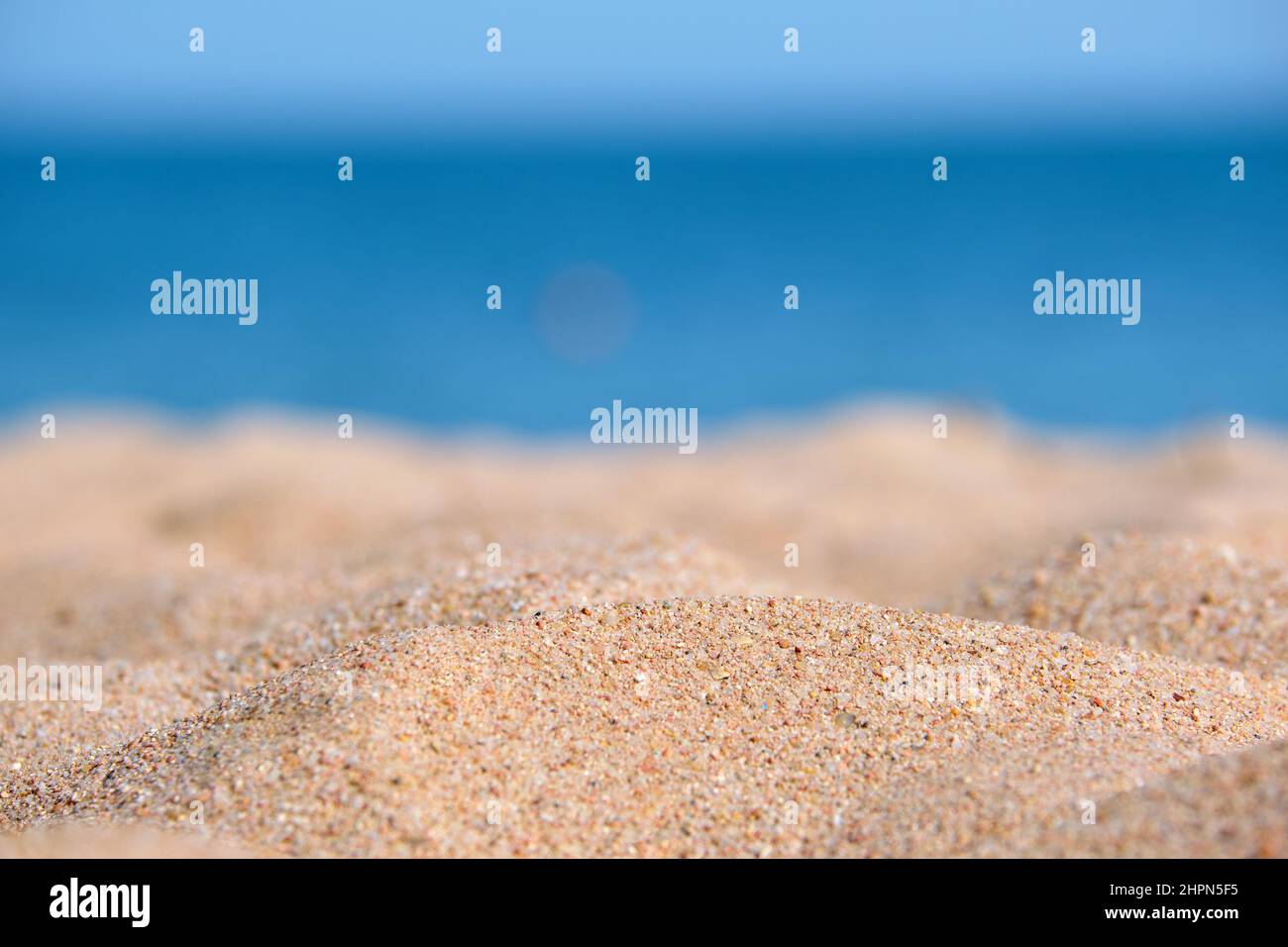 Close up of clean yellow sand surface covering seaside beach with blue ...