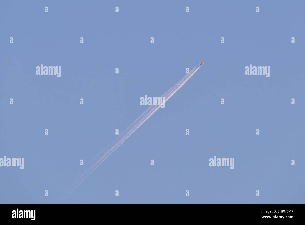 Distant passenger jet plane flying on high altitude on clear blue sky ...