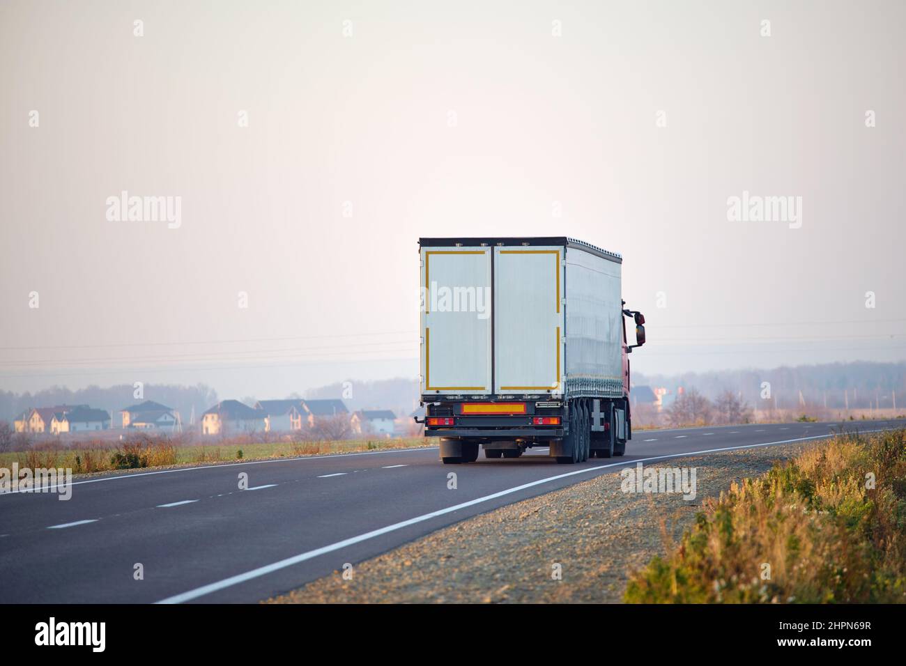 Semi-truck with cargo trailer driving on highway hauling goods in evening. Delivery ...