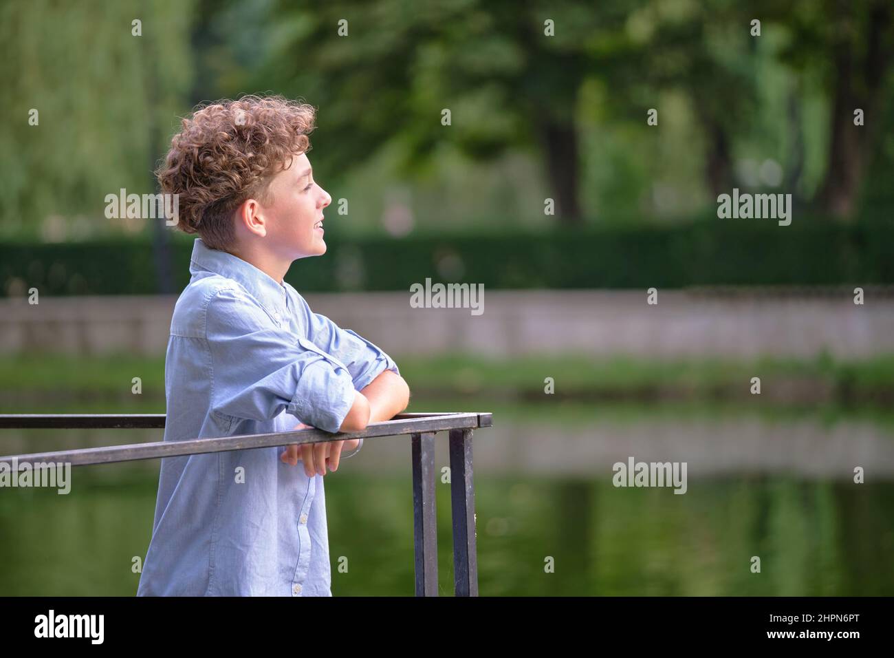 Young happy child boy relaxing in summer park. Positive kid enjoying summertime outdoors. Child ...