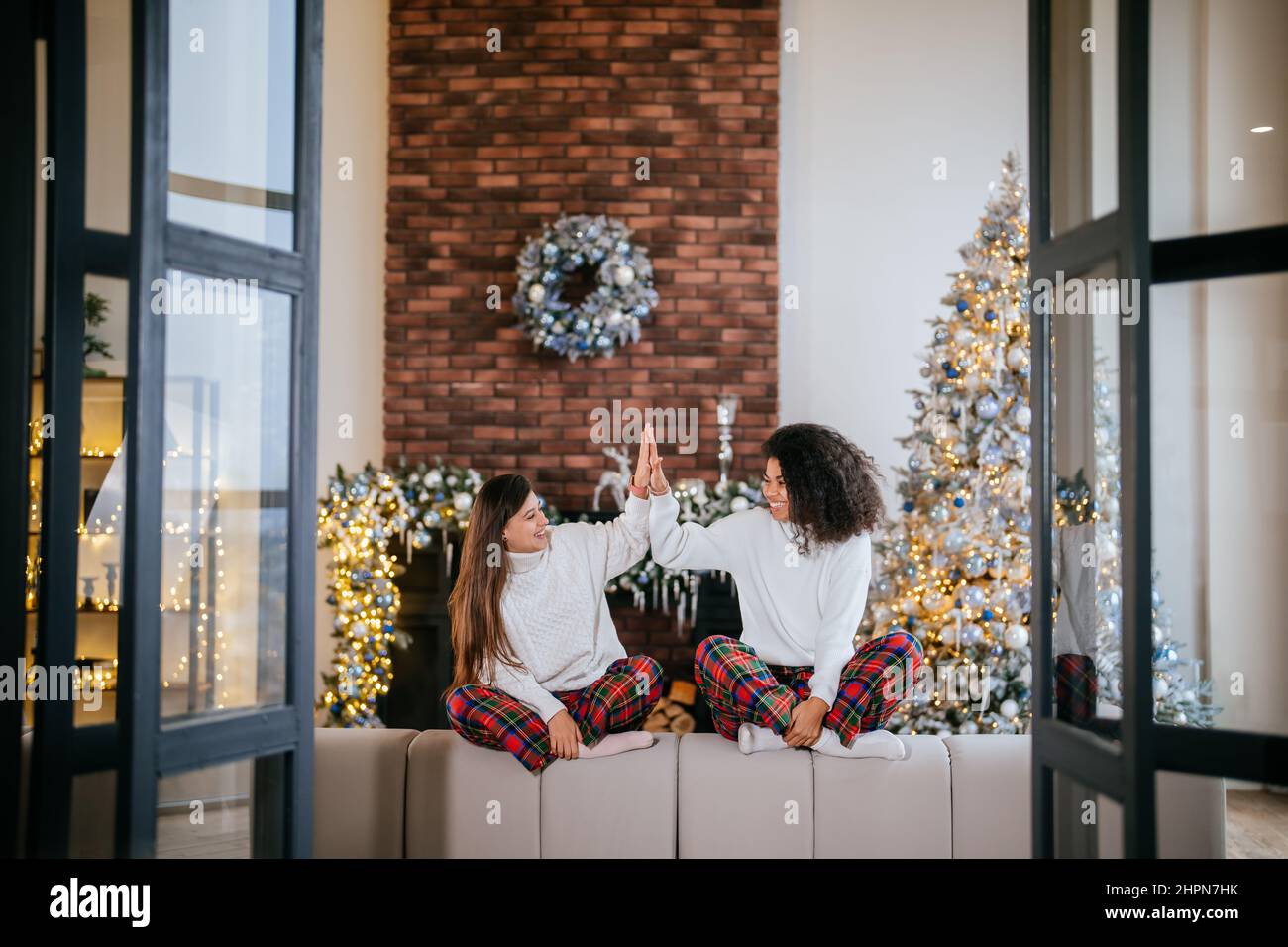 Two female student friends sitting on the couch at home. High five Stock Photo - Alamy
