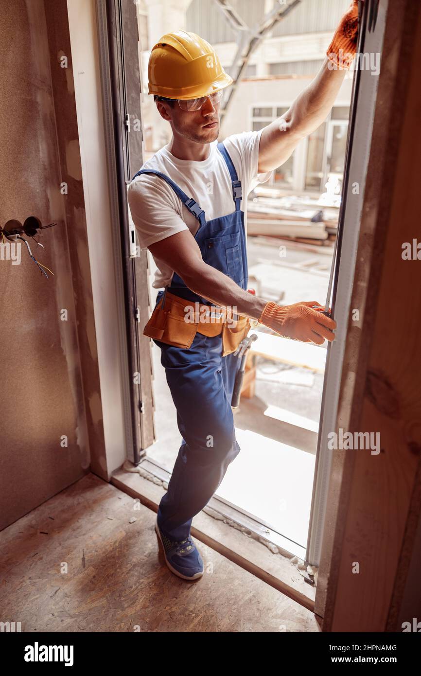 Male builder measuring inside edge of door frame Stock Photo - Alamy