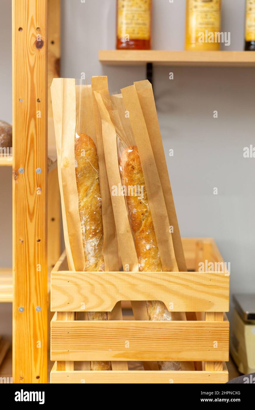 Two fresh baguettes in a package are in a wooden box in a grocery store ...