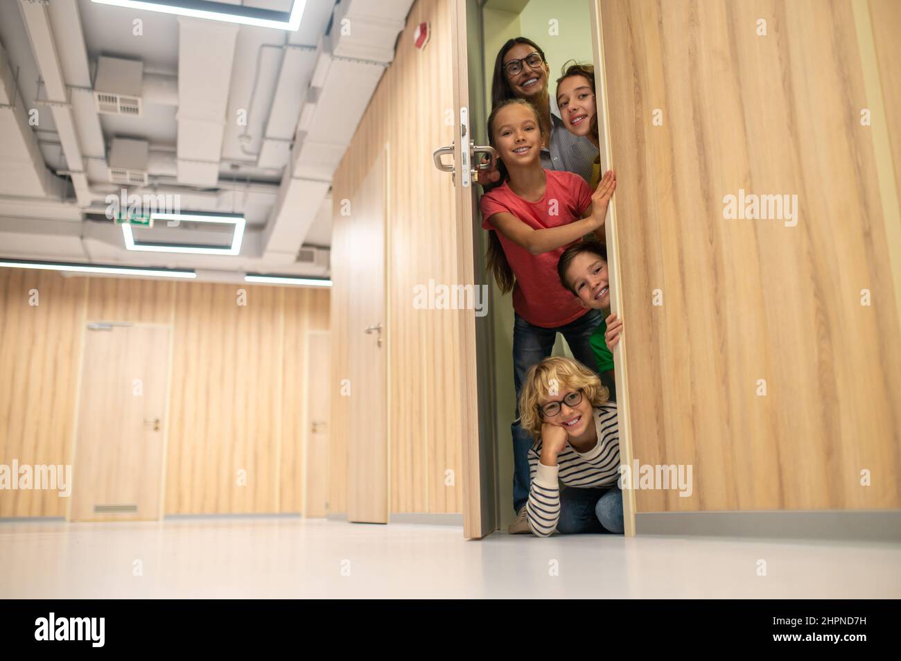 Happy kids with woman opening door looking at camera Stock Photo - Alamy